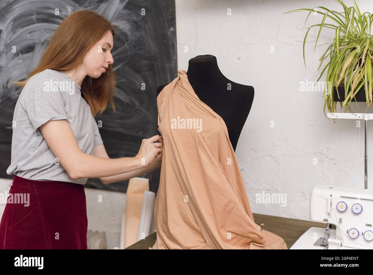 Seamstress tries on fabric on a black mannequin in a sewing workshop ...