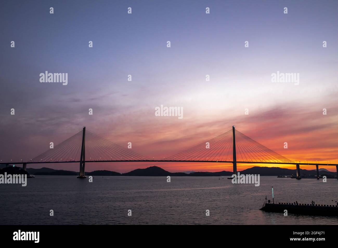High angle shot of the bright sun setting behind a big bridge over the ...