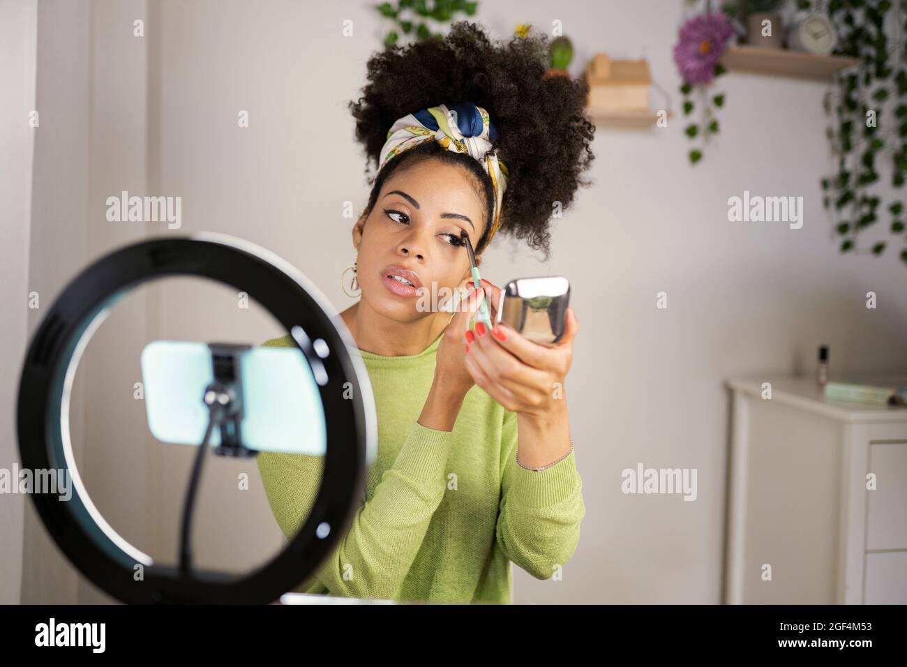 Female influencer giving make-up tutorial through vlogging at home ...
