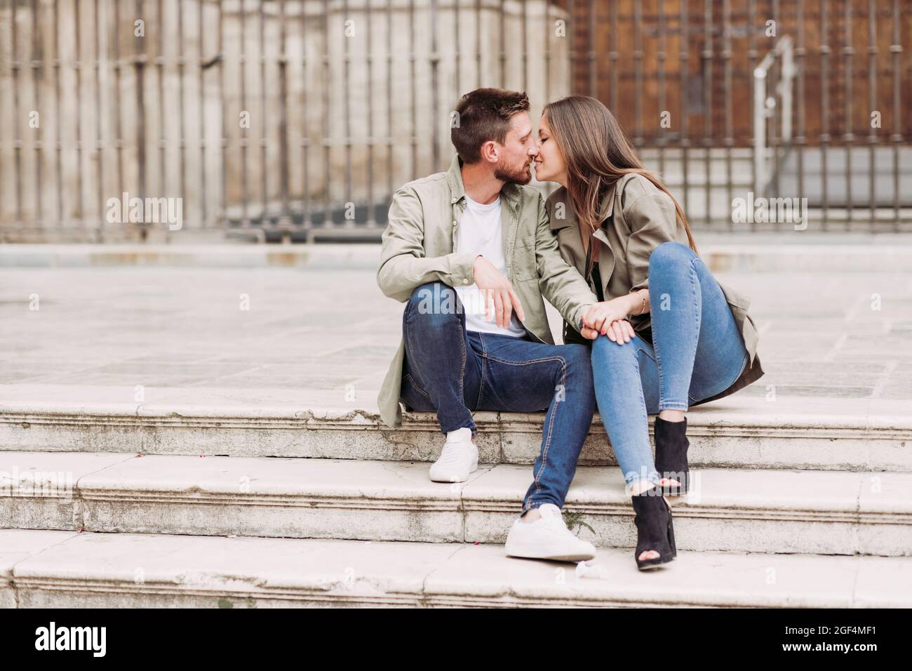 Couple kissing each other while sitting on steps Stock Photo - Alamy