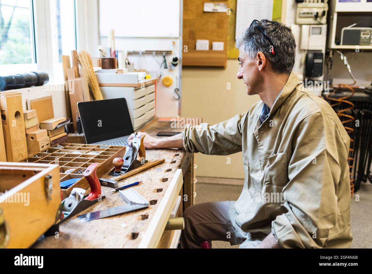 Male craftsperson using laptop on table at workshop Stock Photo - Alamy