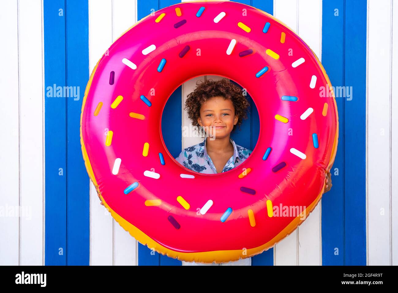 Cute smiling boy looking through inflatable doughnut Stock Photo - Alamy