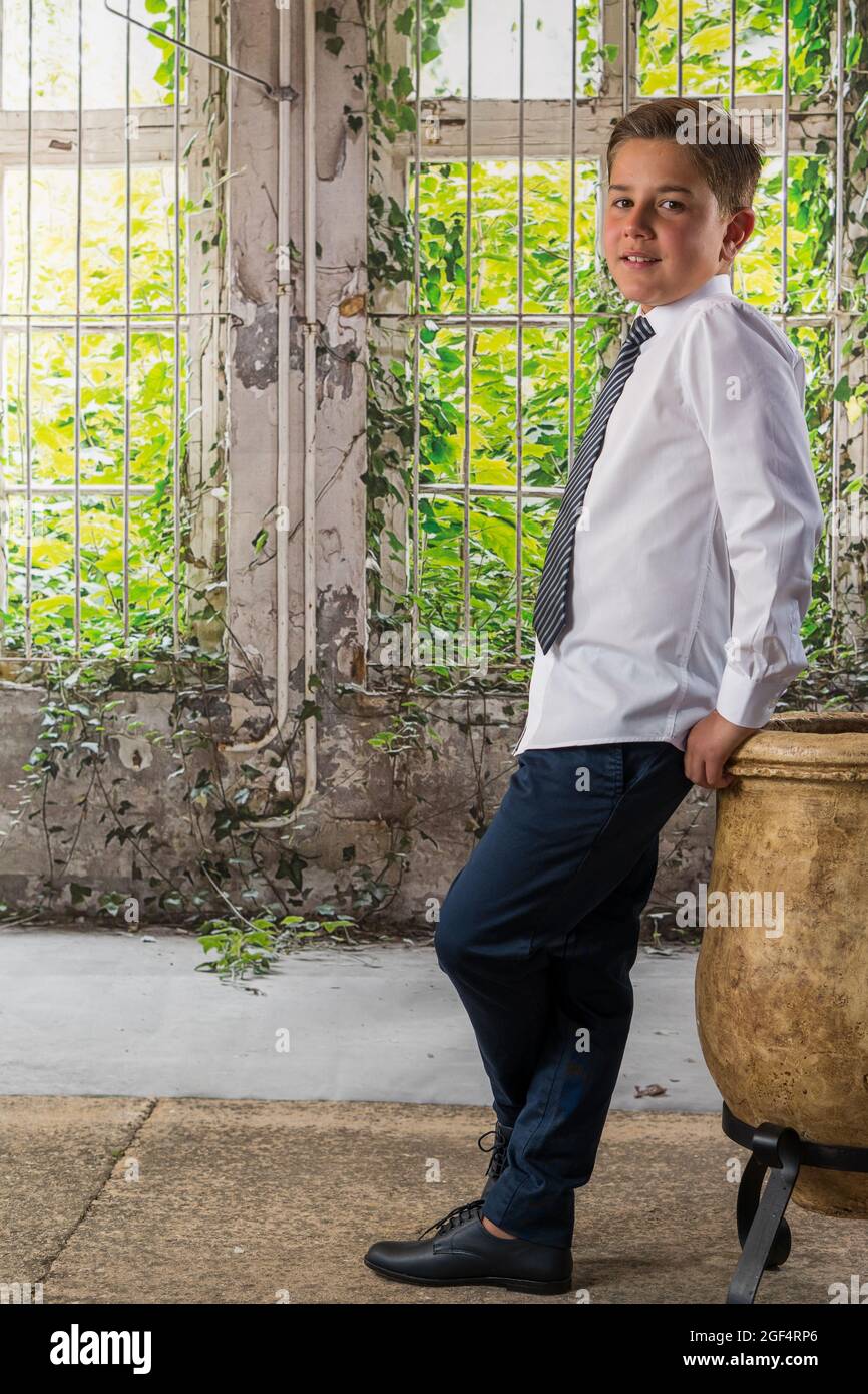 Vertical closeup of a young boy in a white shirt with a tie posing ...