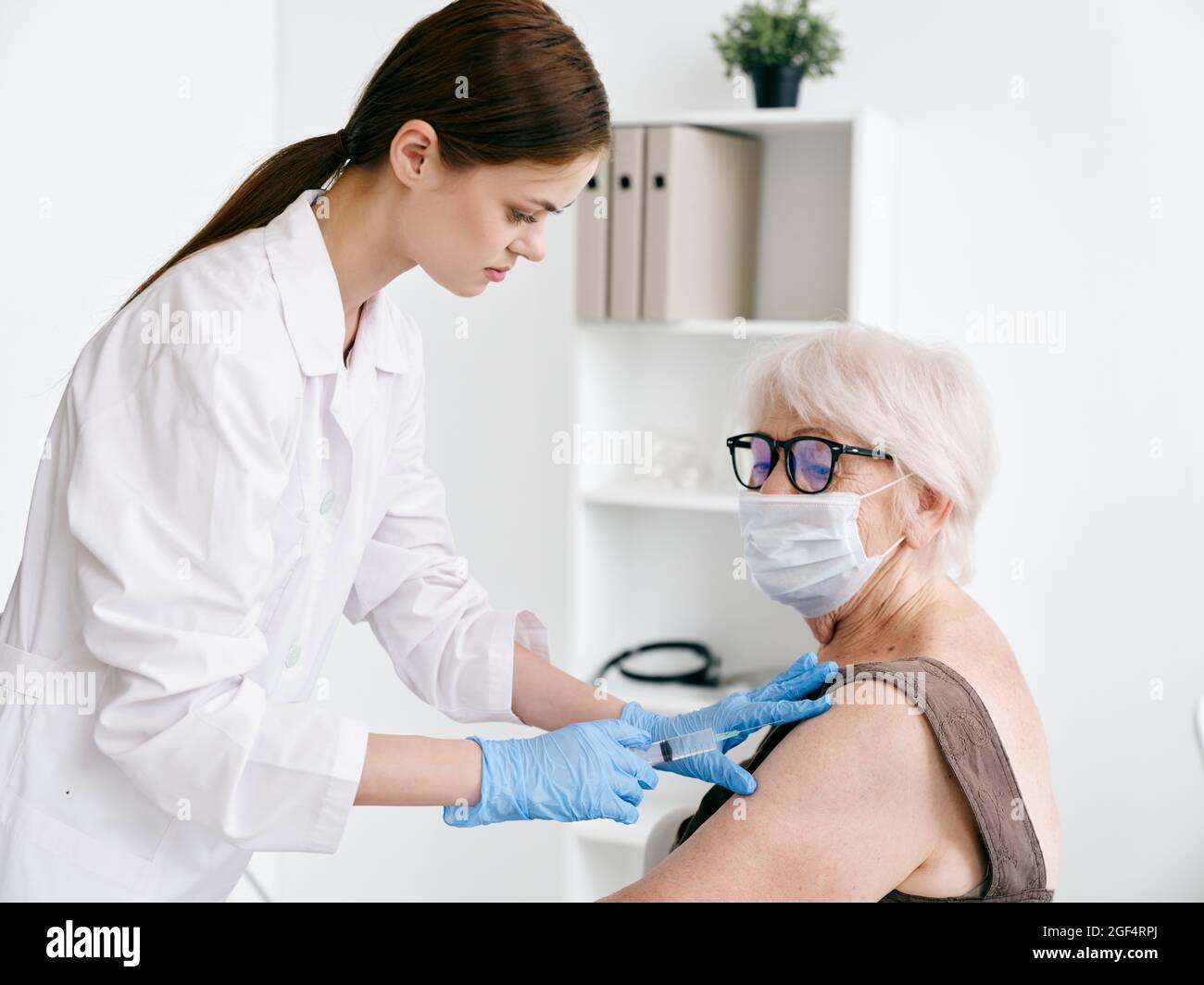 Nurse giving an injection to an elderly patient covid passport hospital ...