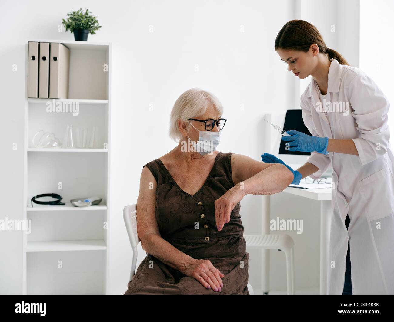 Nurse giving injection to an elderly woman hospital vaccine passport ...