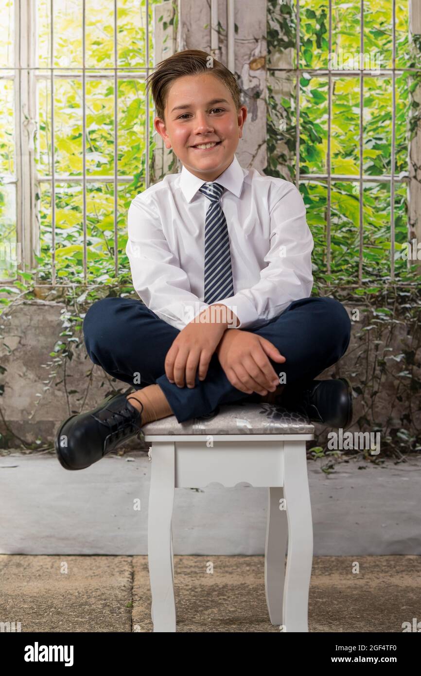 Vertical closeup of a young boy in a white shirt with a tie posing ...