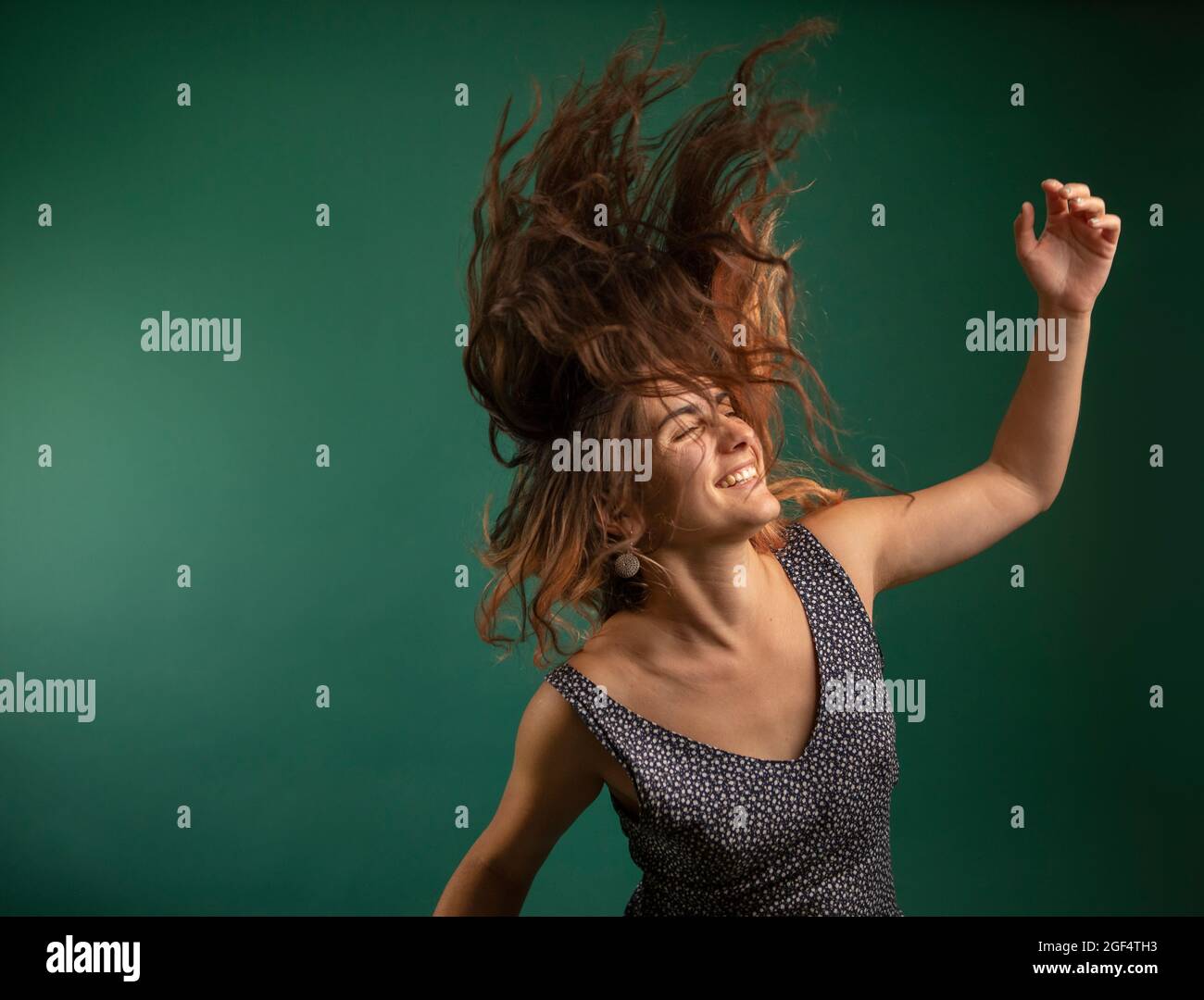Happy woman tossing hair against green background Stock Photo - Alamy