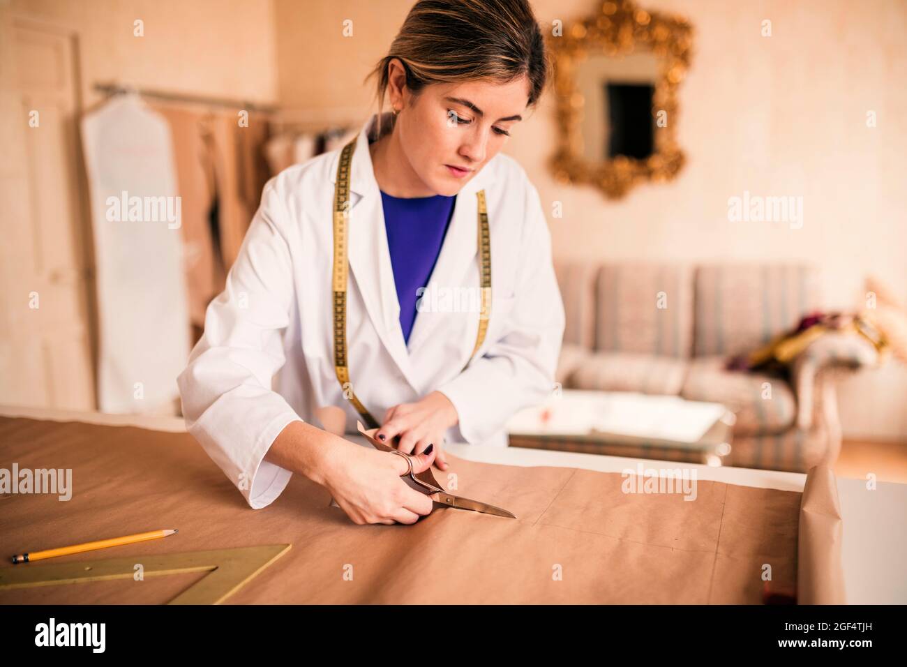 Young female tailor cutting fabric with scissor at workbench Stock ...