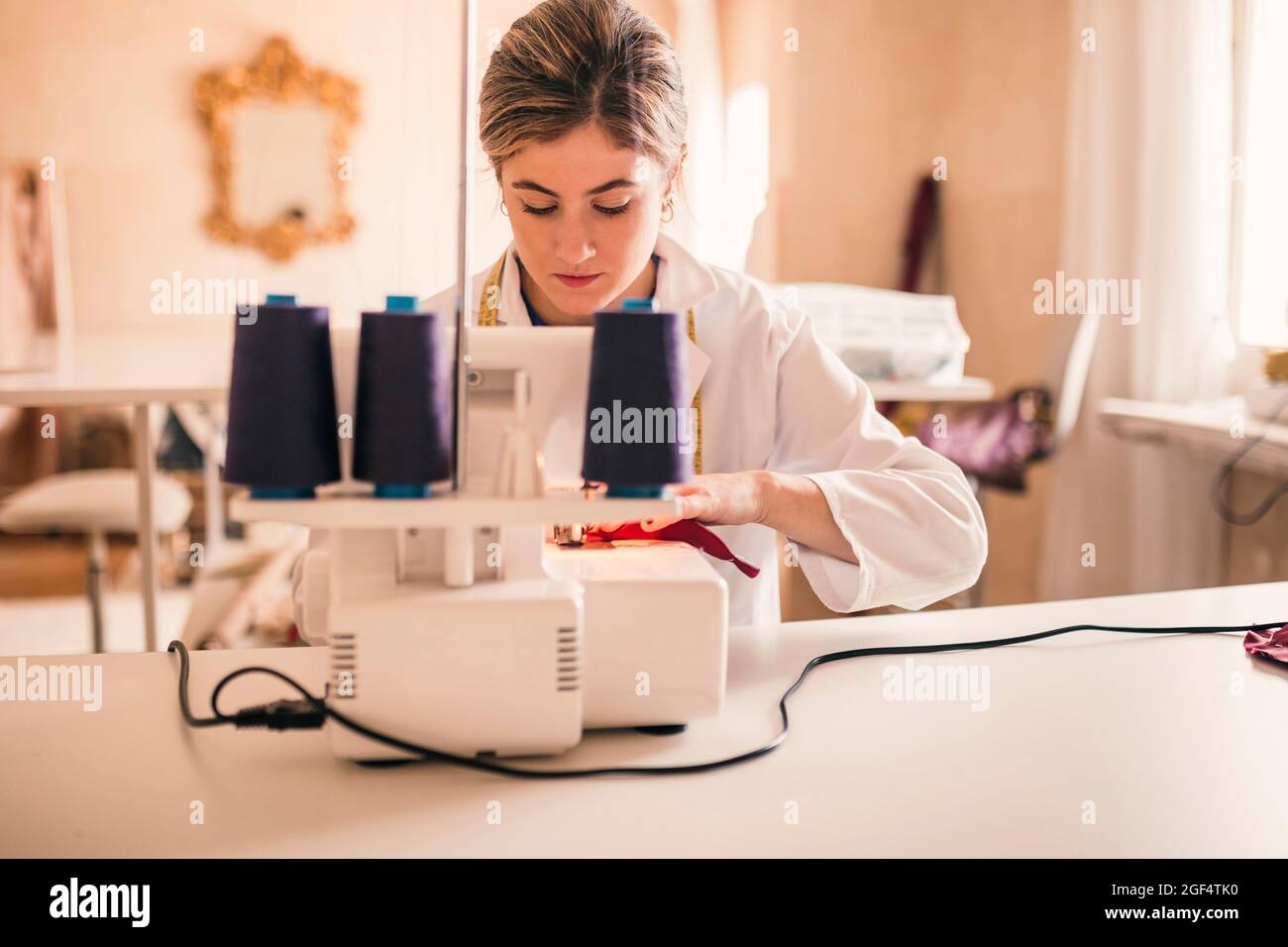 Young female tailor using sewing machine at workbench Stock Photo - Alamy