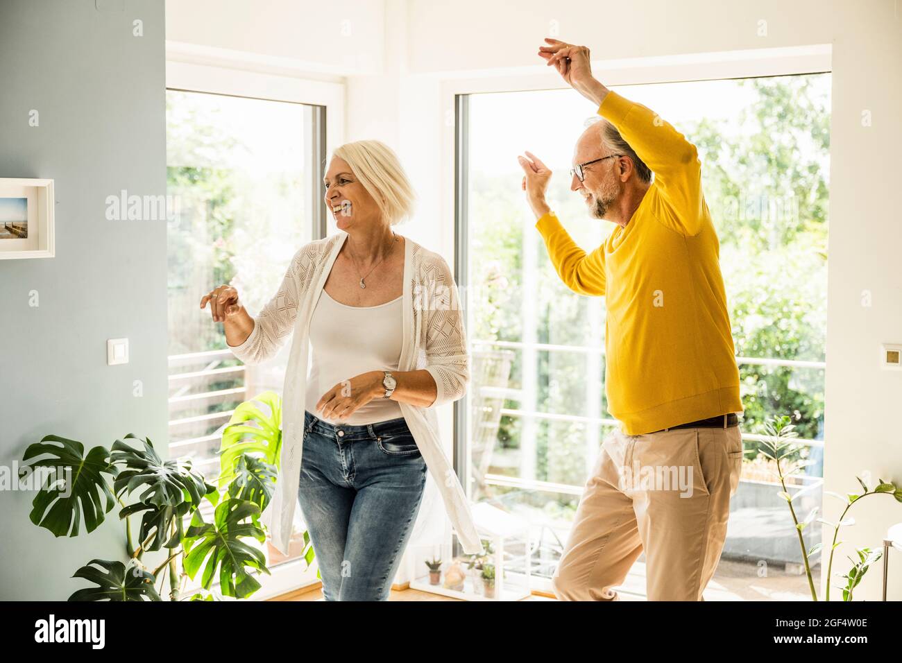 Carefree mature man with hand raised dancing with woman at home Stock ...