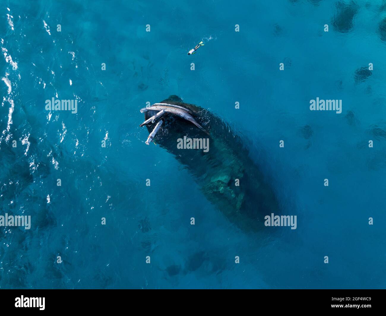 Aerial view of lone man snorkeling around sunken shipwreck Stock Photo ...