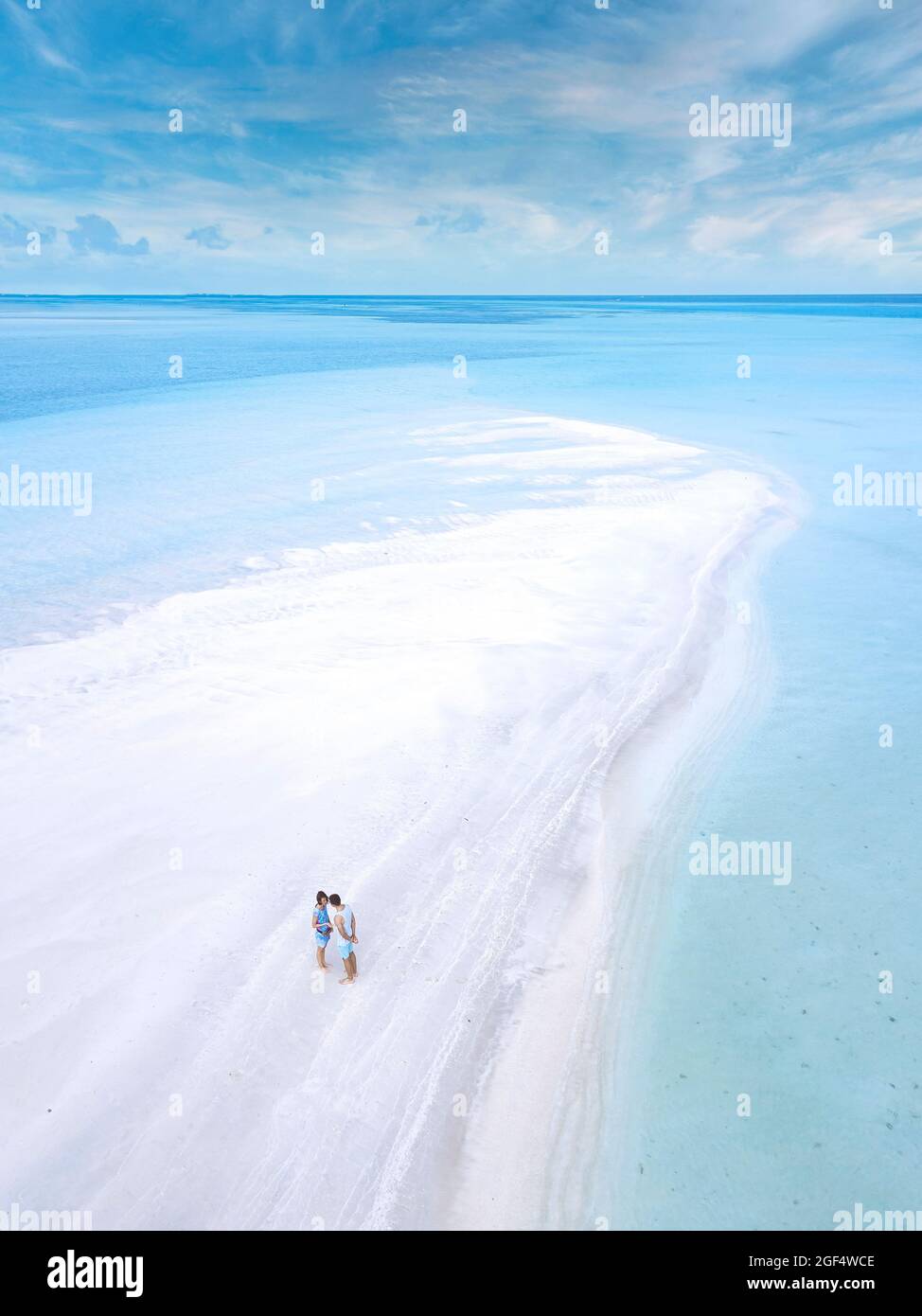 Aerial view of young couple standing together on sandy coastal beach of ...
