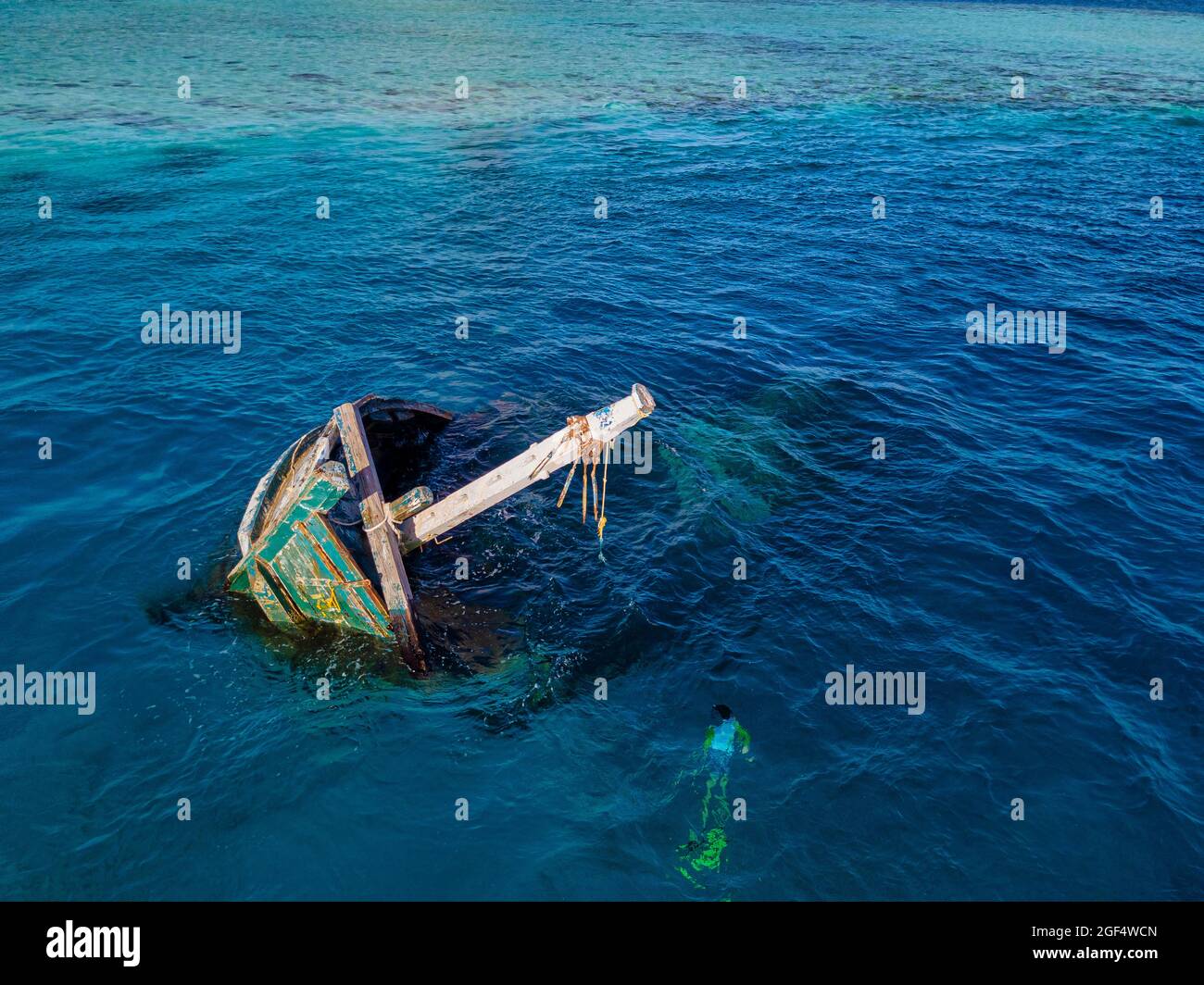 Aerial view of lone man snorkeling around sunken shipwreck Stock Photo ...