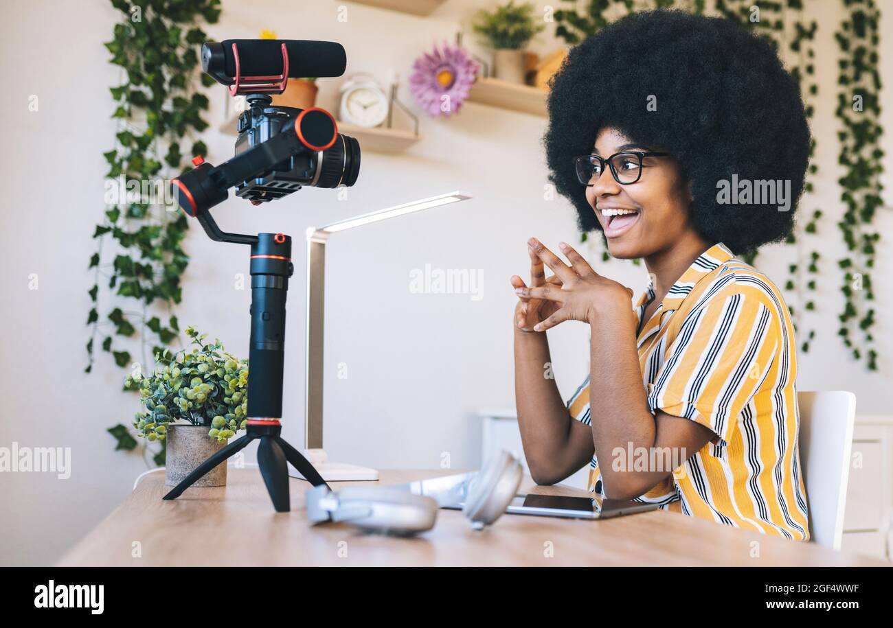 Cheerful female influencer with hands clasped vlogging at home Stock ...