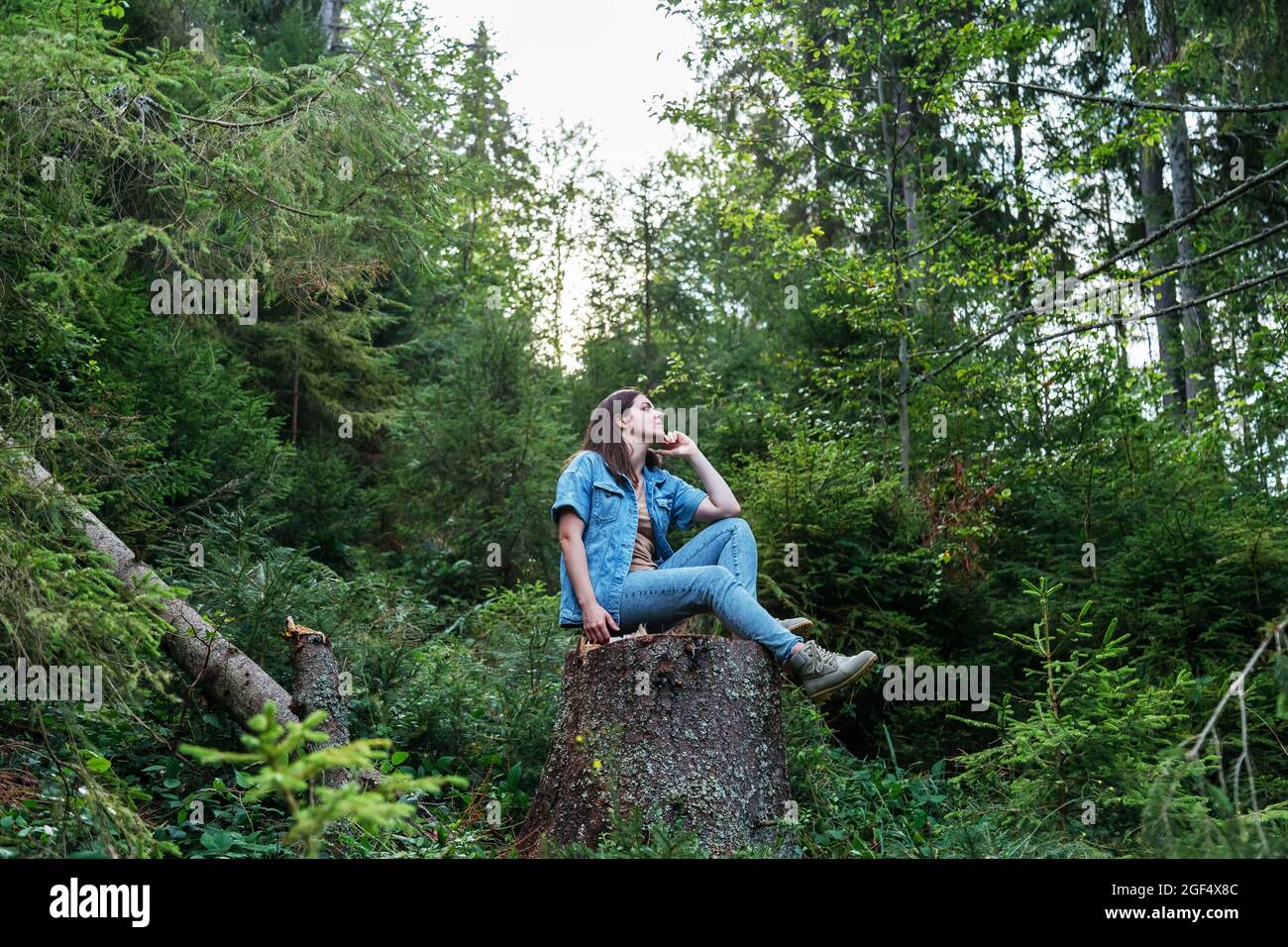 Woman resting in forest in park. dressed in denim suit and boots. Young ...