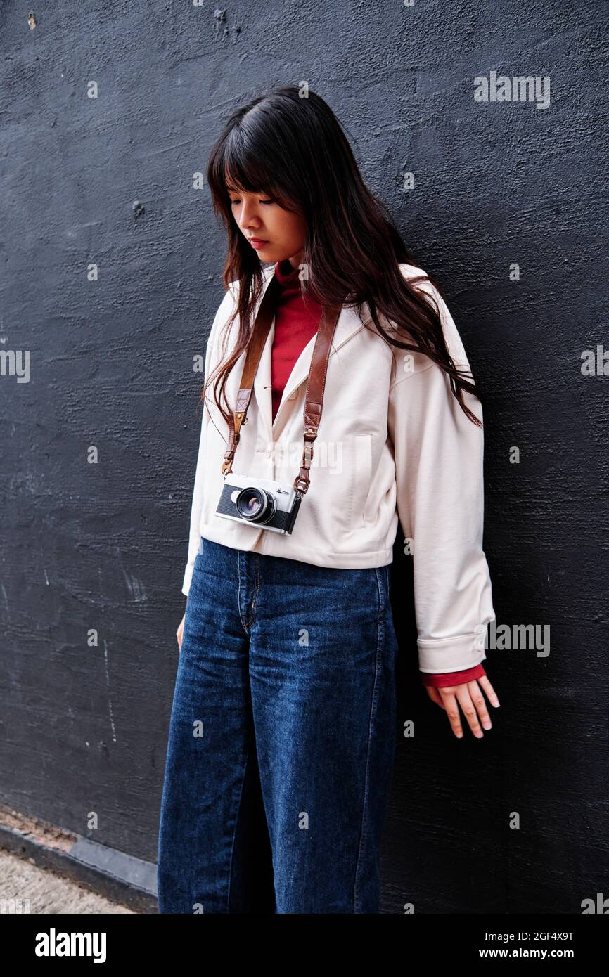Lonely woman looking down while leaning on black wall Stock Photo - Alamy