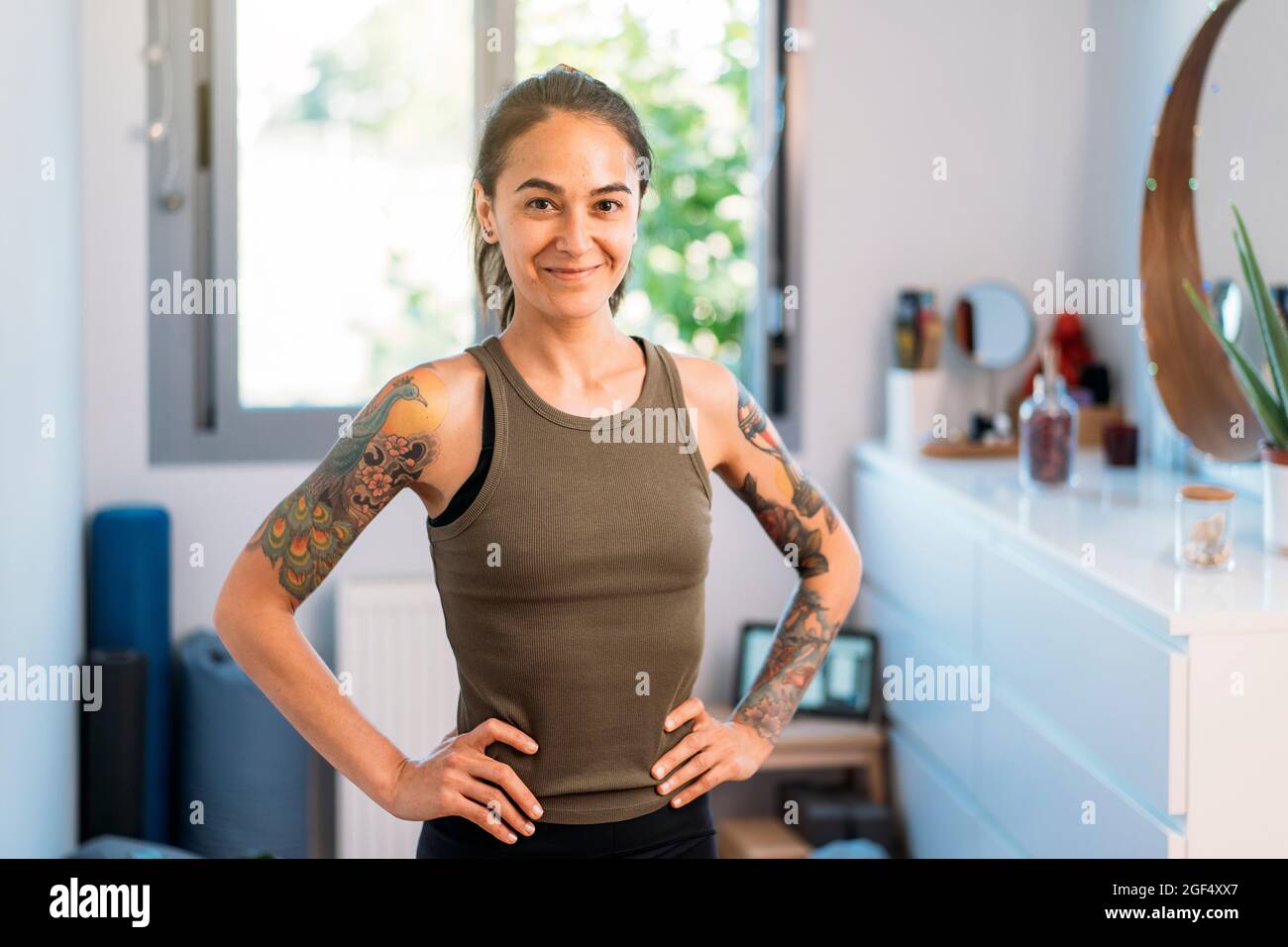 Smiling woman with hands on hip standing at home Stock Photo - Alamy