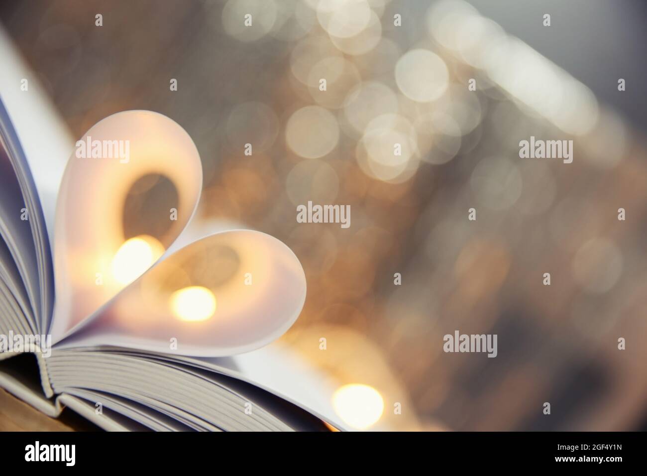 Sheets of book curved into heart shape on unfocused lights Stock Photo ...