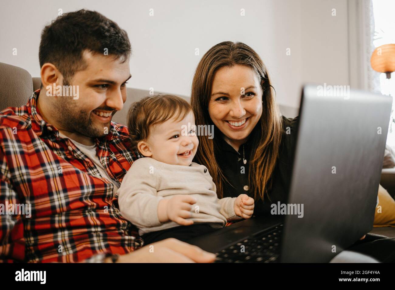 Baby boy with parents smiling while talking during video call through ...