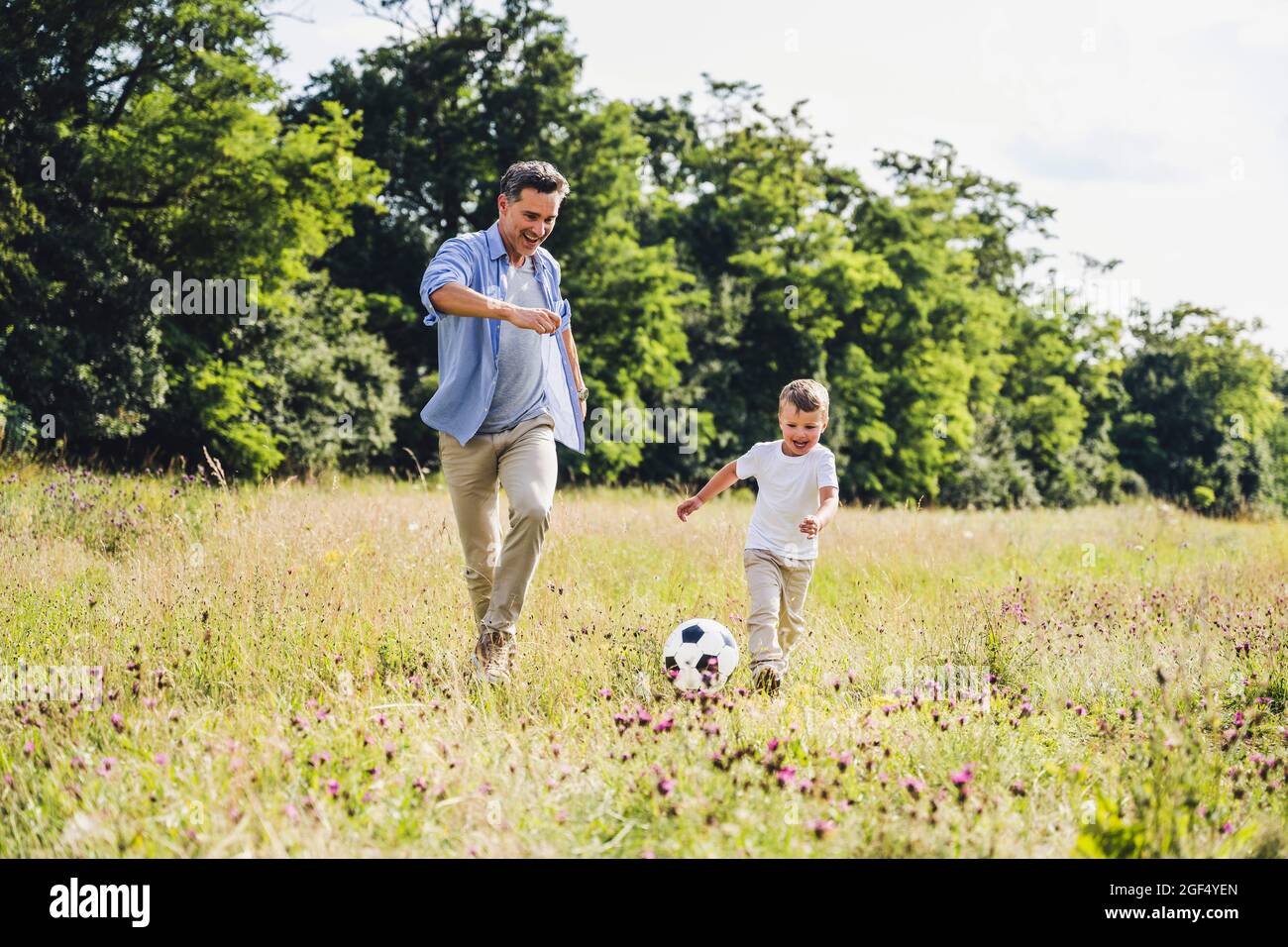 Cheerful father and son playing soccer on grass Stock Photo - Alamy