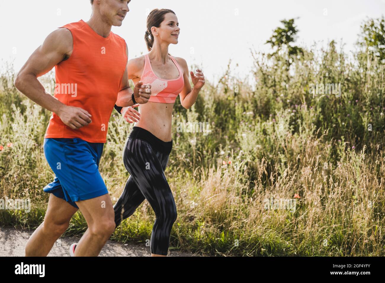 Male and female athletes running together by meadow Stock Photo - Alamy