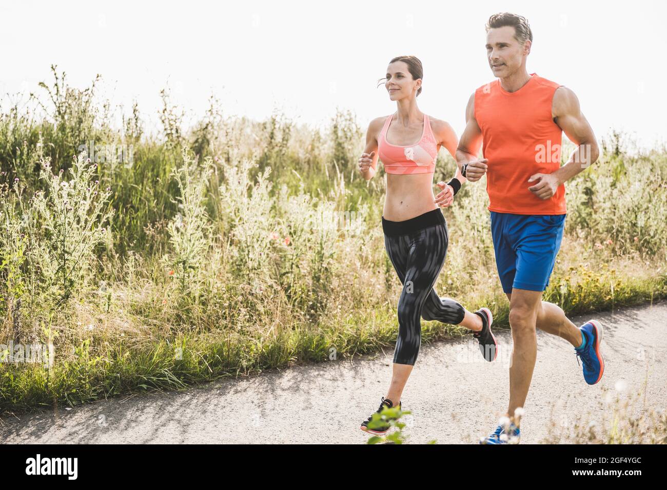 Sports people running together during sunny day Stock Photo - Alamy