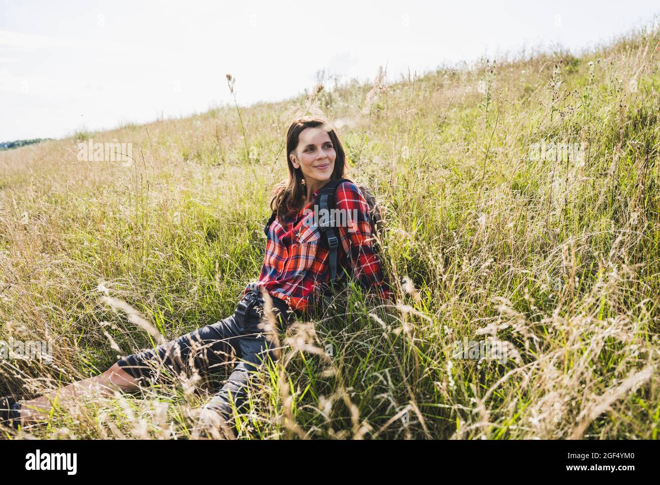 Female hiker resting while sitting on grass Stock Photo - Alamy