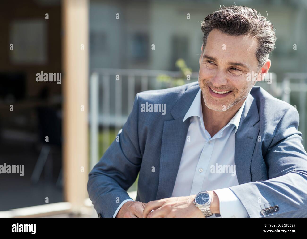 Thoughtful businessman smiling during sunny day Stock Photo - Alamy