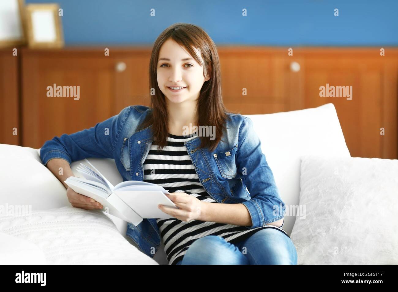 Beautiful girl reading book on sofa, indoor Stock Photo - Alamy