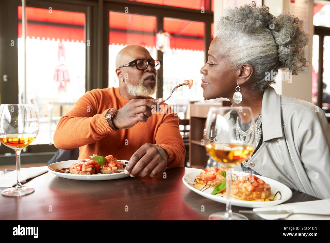 Mature man feeding woman while sitting at restaurant Stock Photo - Alamy