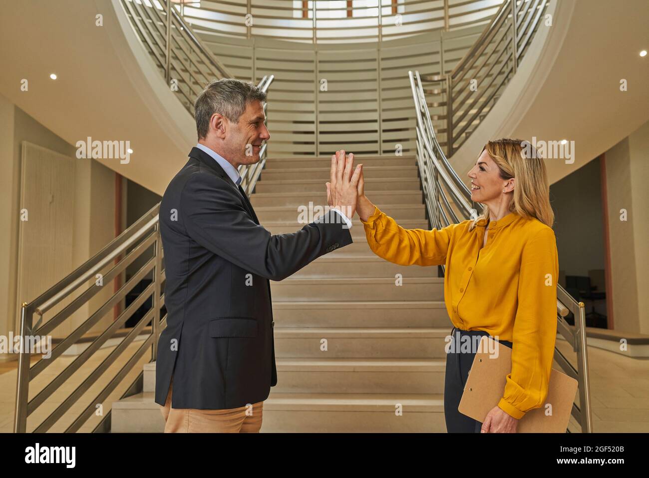 Male and female colleagues giving high-five at workplace Stock Photo ...