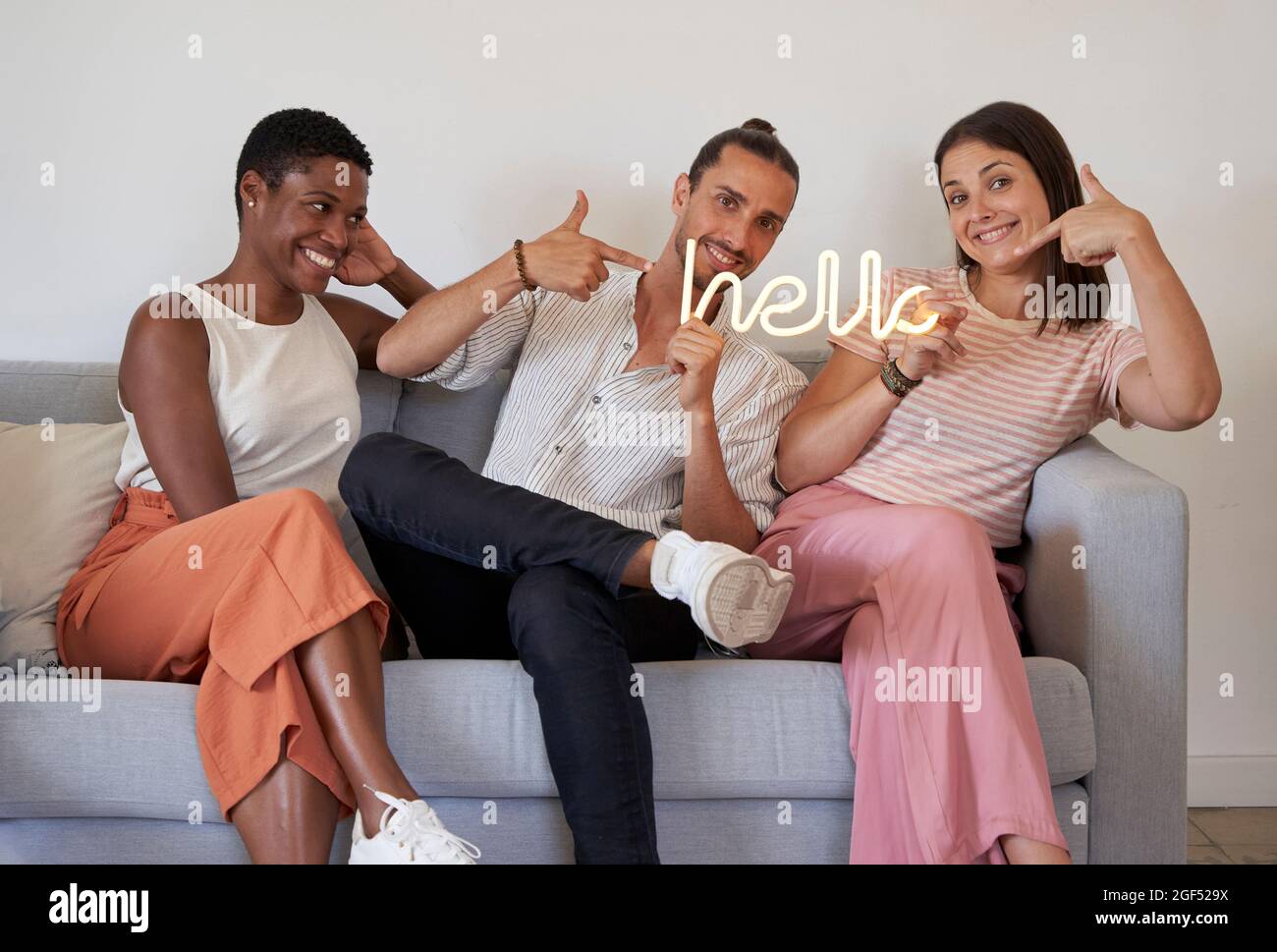 Happy male and female coworkers pointing at Hello sign illuminated text ...