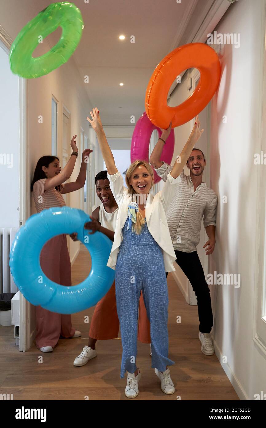 Playful male and female colleagues playing with inflatable rings at ...