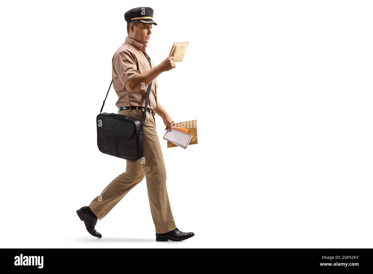 Full length profile shot of a mailman walking and reading a letter ...