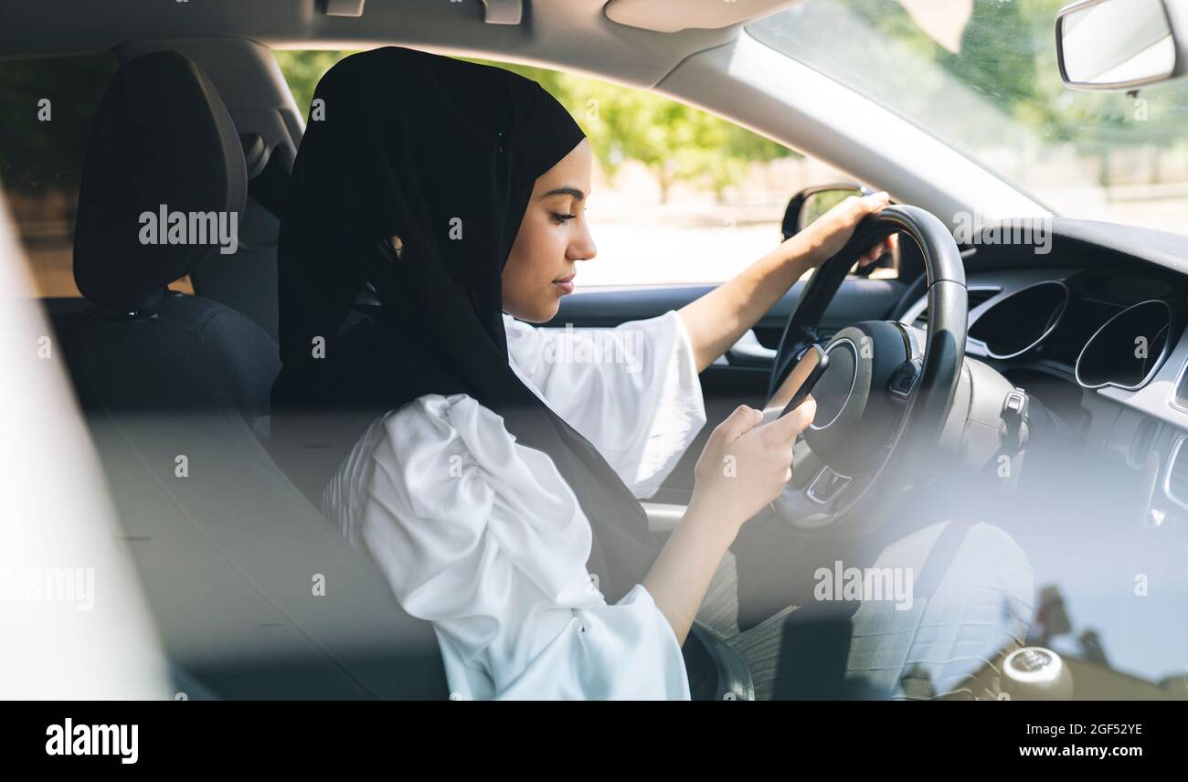 Woman text messaging through mobile phone while driving car Stock Photo ...