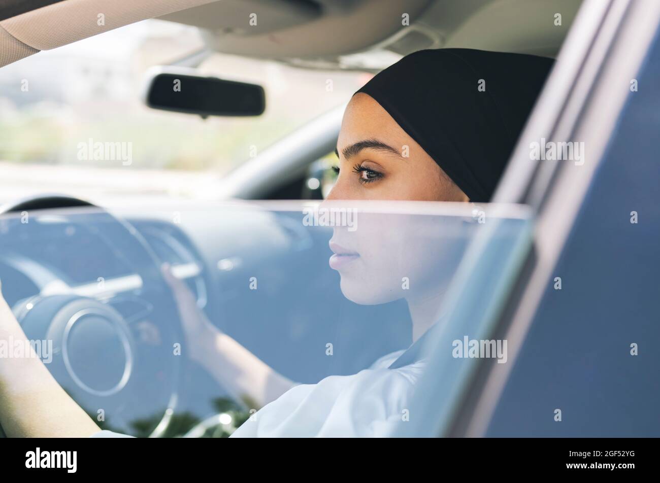 Woman looking through window while driving car Stock Photo - Alamy