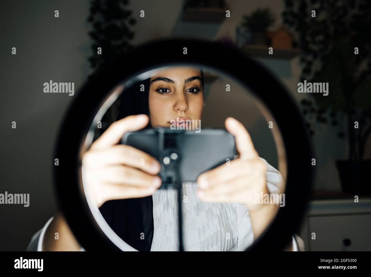 Female vlogger adjusting mobile phone while vlogging at home Stock ...