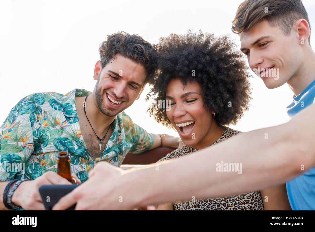 Cheerful male and female friends sharing smart phone during weekend ...