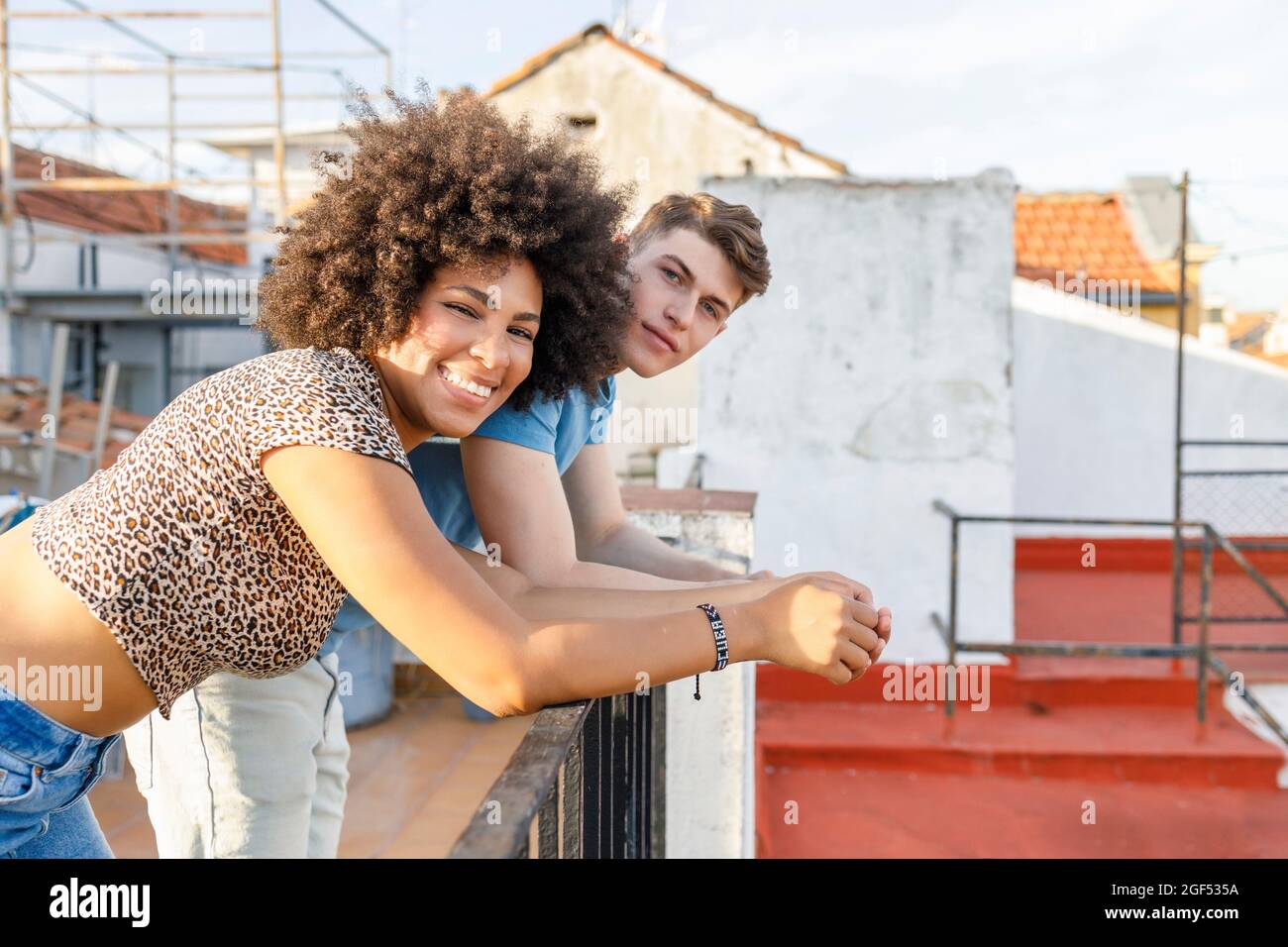 Smiling young couple leaning on railing at terrace Stock Photo - Alamy