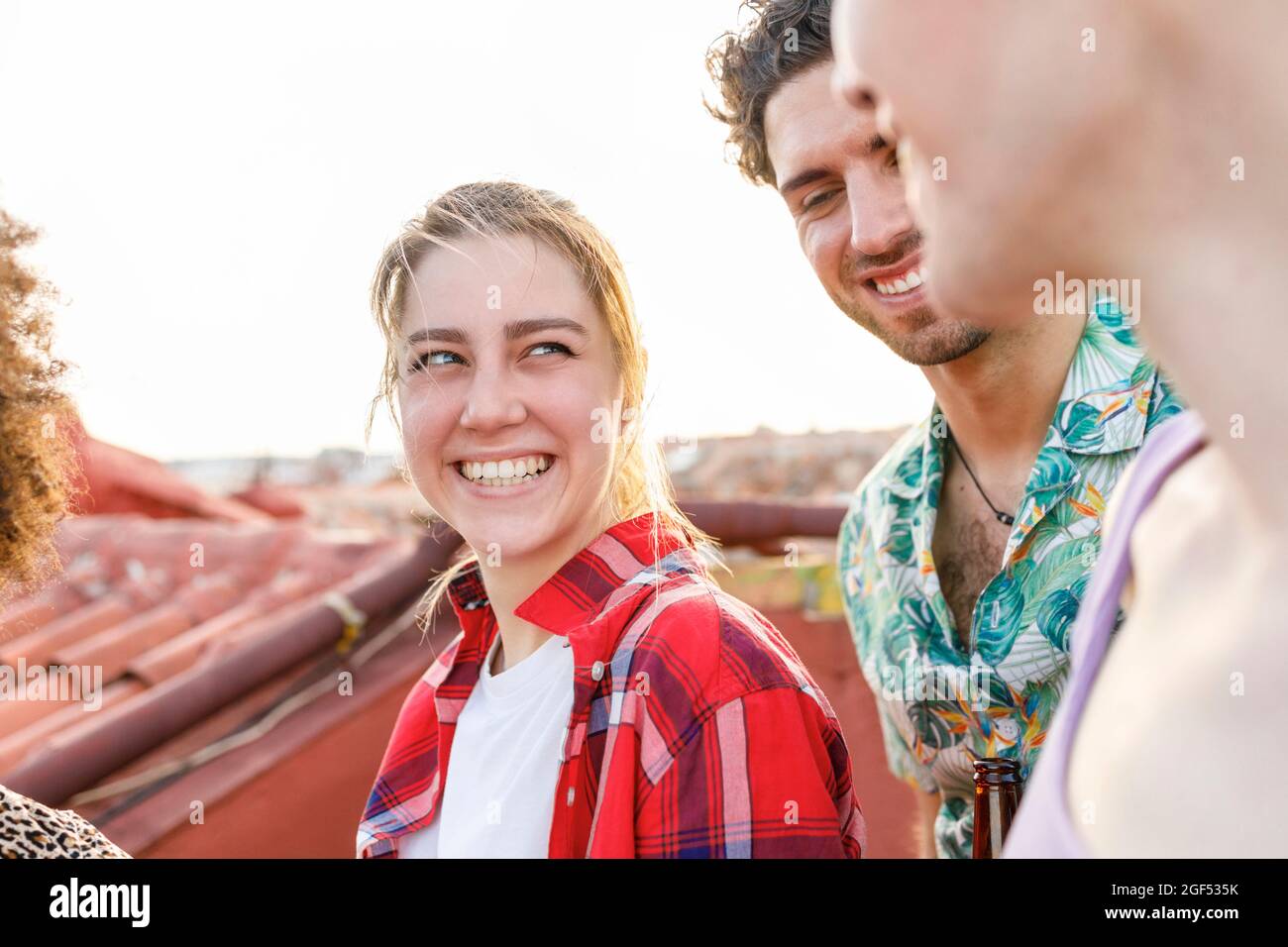 Happy young woman looking at friend on rooftop Stock Photo - Alamy