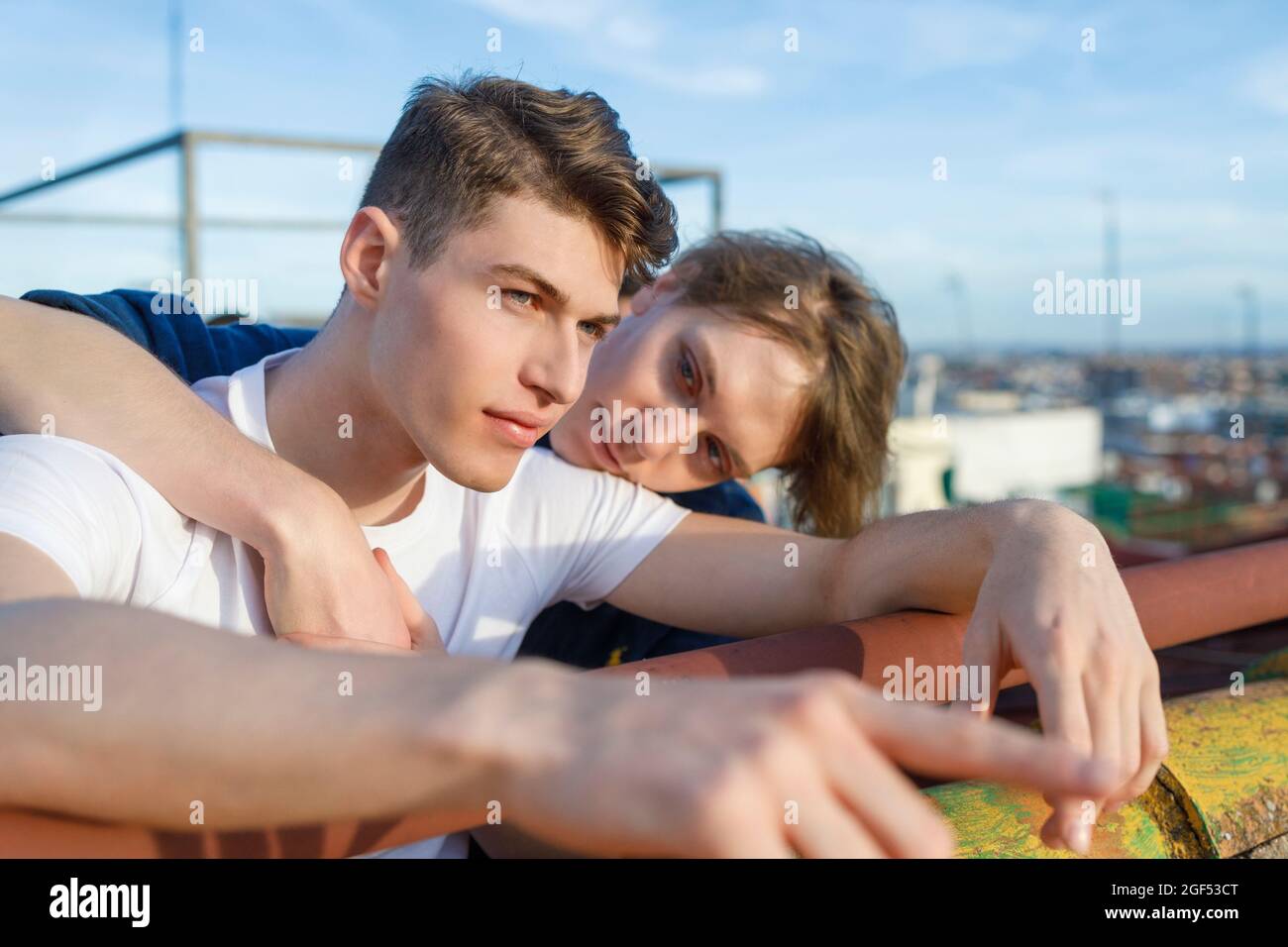 Young man looking at male friend on rooftop Stock Photo - Alamy