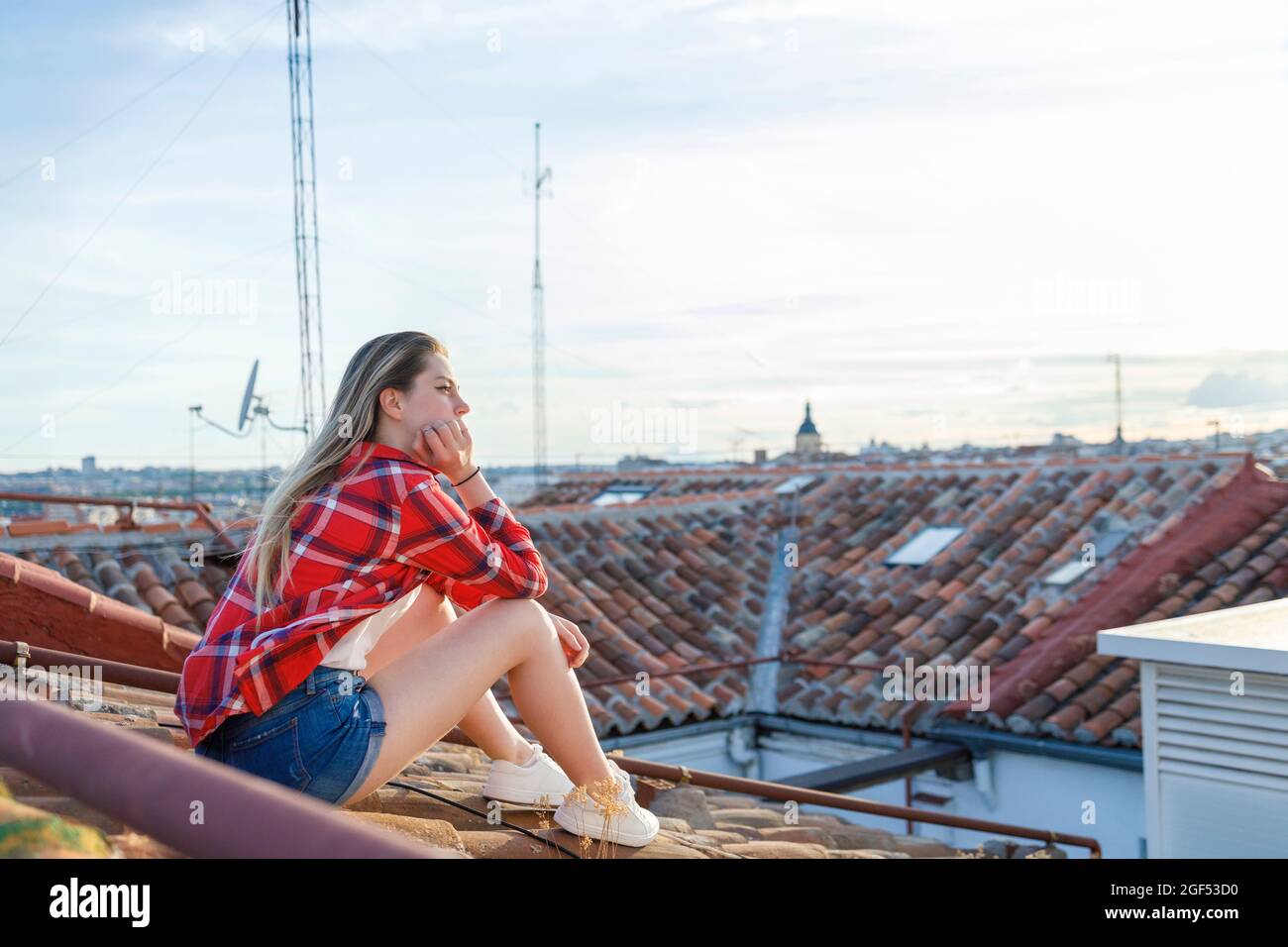 Young woman day dreaming while sitting on rooftop Stock Photo - Alamy