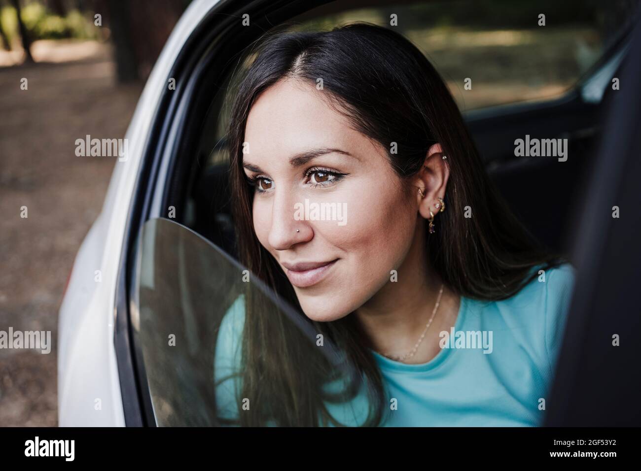 Beautiful young woman looking through car window Stock Photo - Alamy