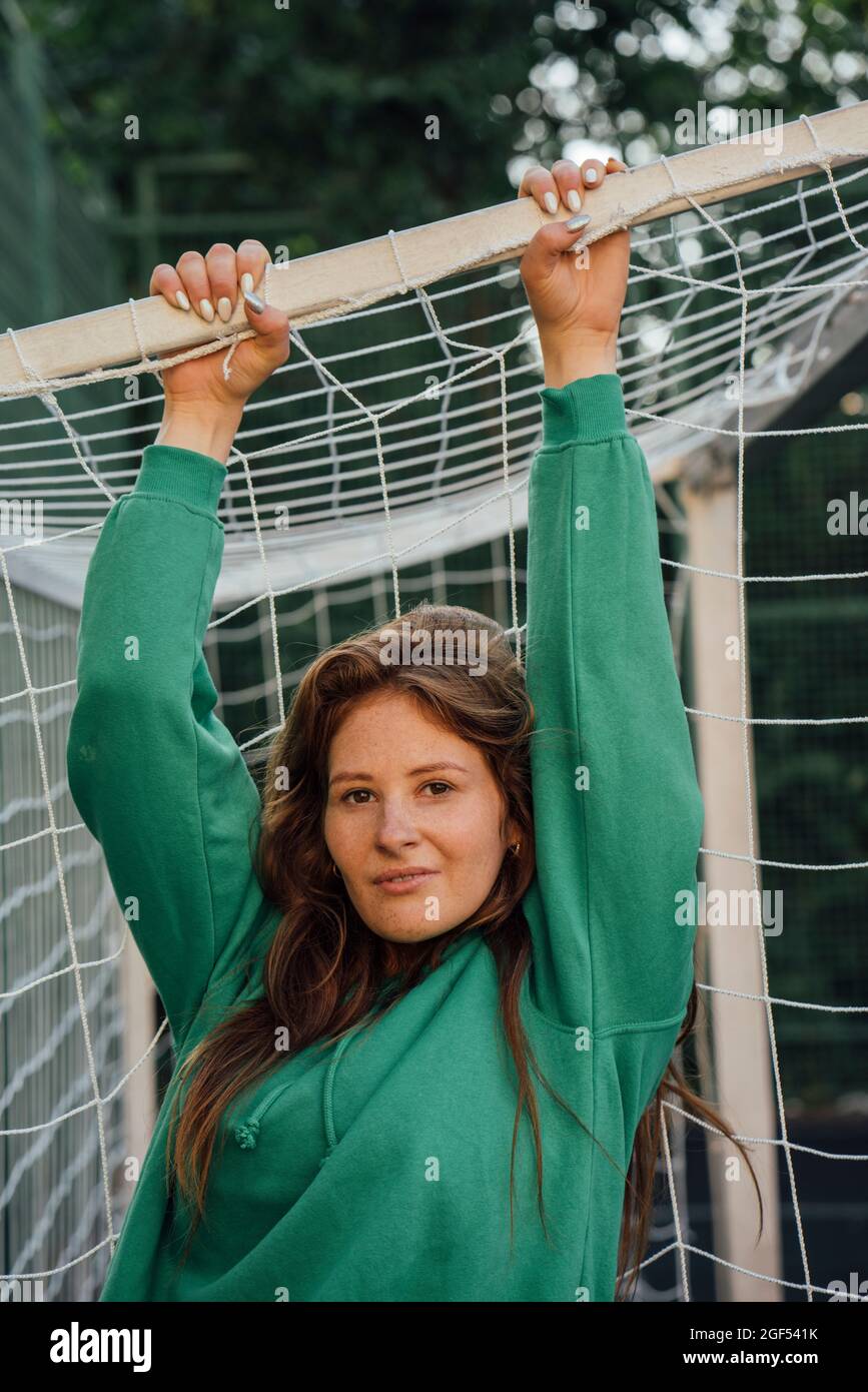 Young woman hanging from goal post in public park Stock Photo - Alamy