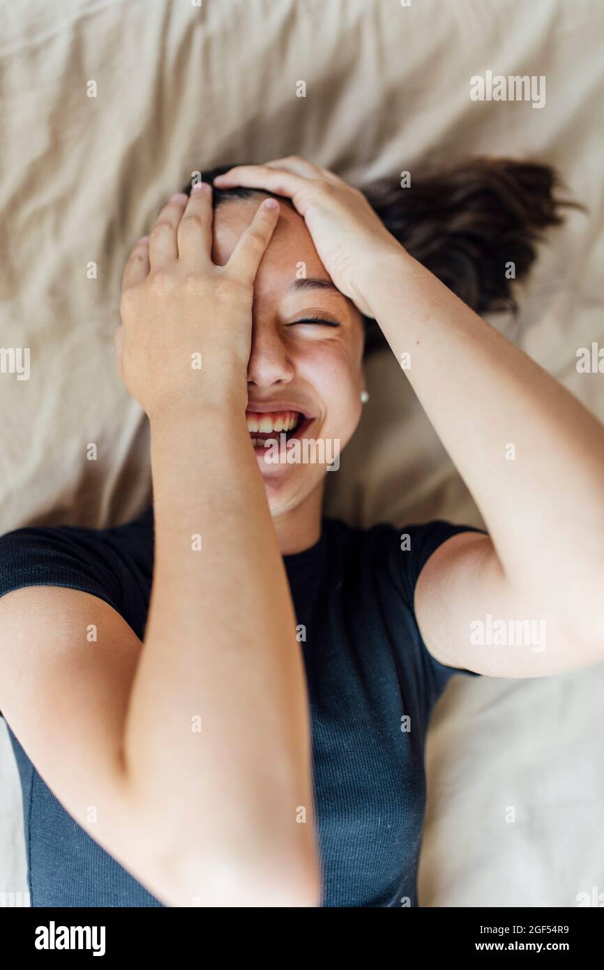 Happy girl covering face while lying on bed at home Stock Photo - Alamy