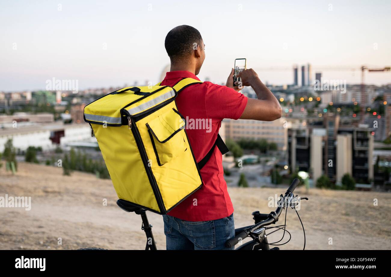 Male delivery person photographing city through smart phone Stock Photo ...