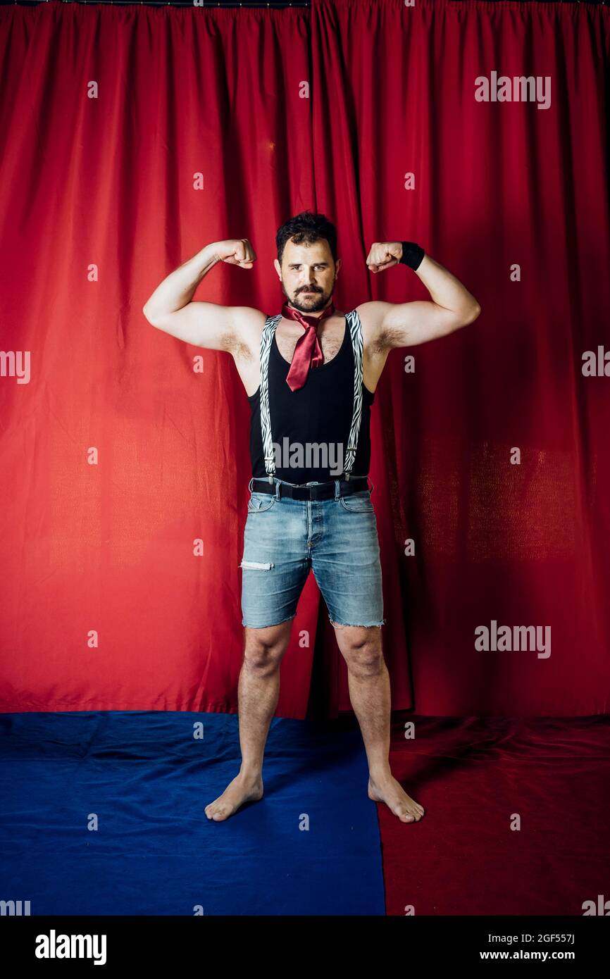 Male acrobat flexing muscles while standing on stage Stock Photo - Alamy