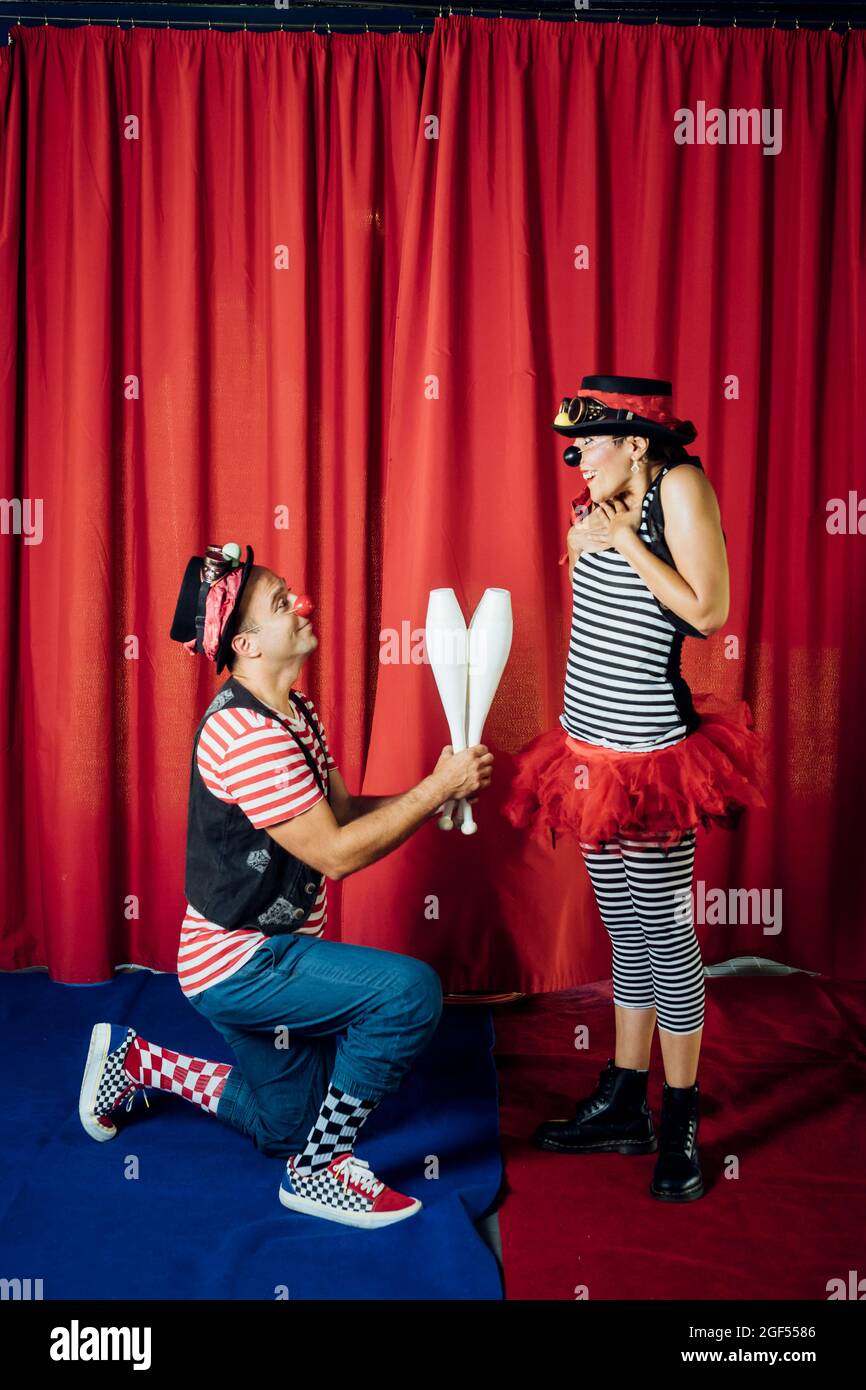 Male performer with juggling pins looking at female acrobat while ...