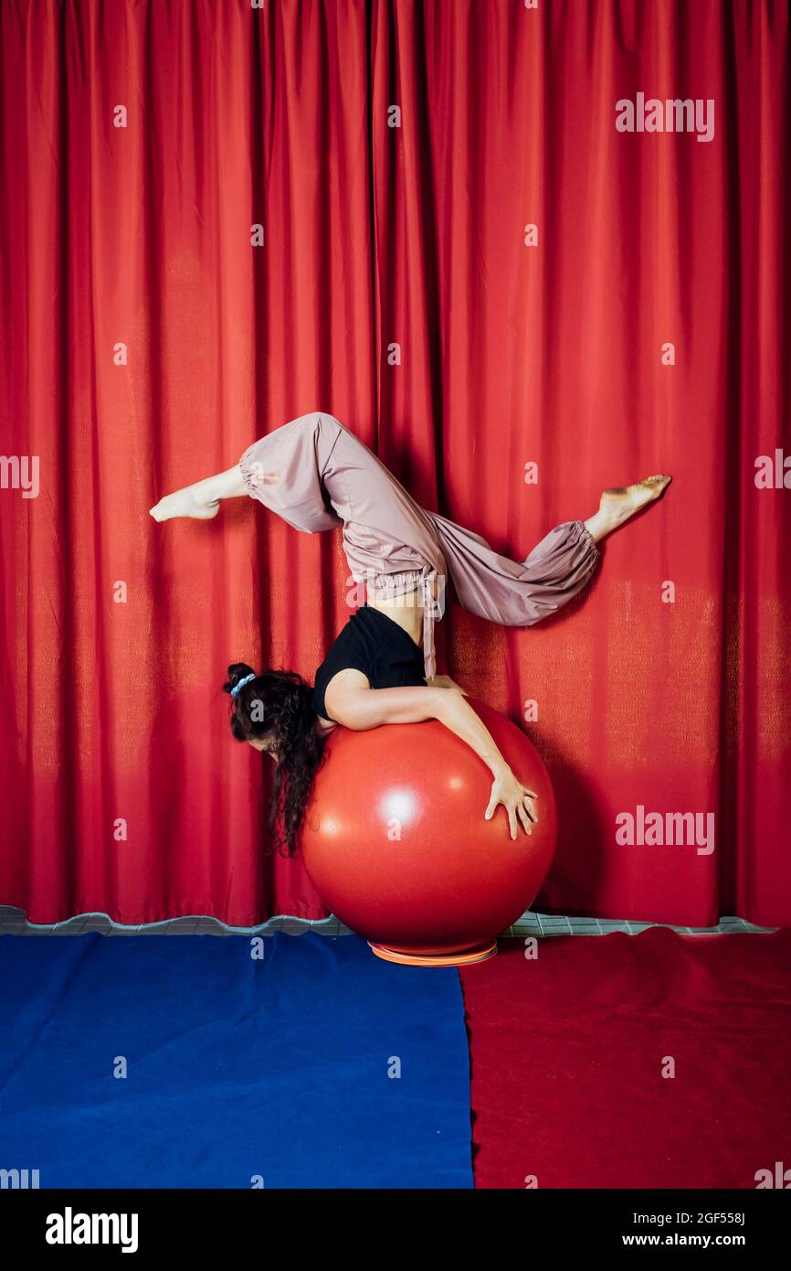 Female circus performer balancing on red ball Stock Photo - Alamy