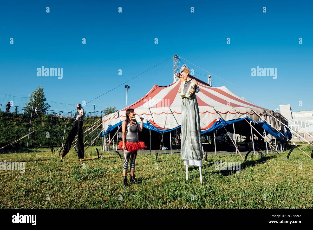 Female acrobat looking at performer playing accordion while standing ...